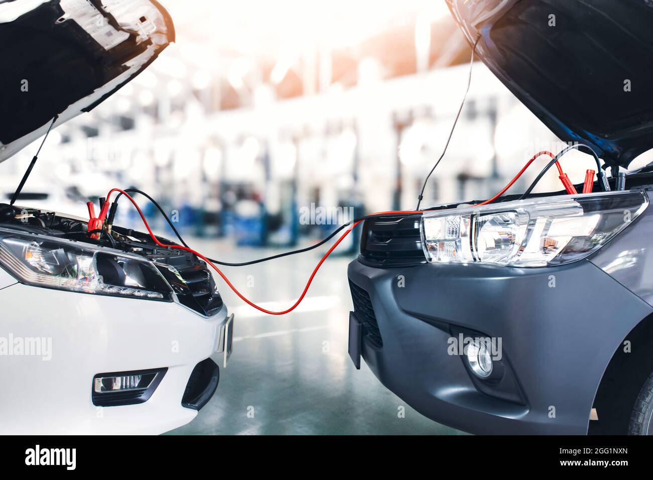 Sedan car jumper the battery cables to the pickup truck in repair ...