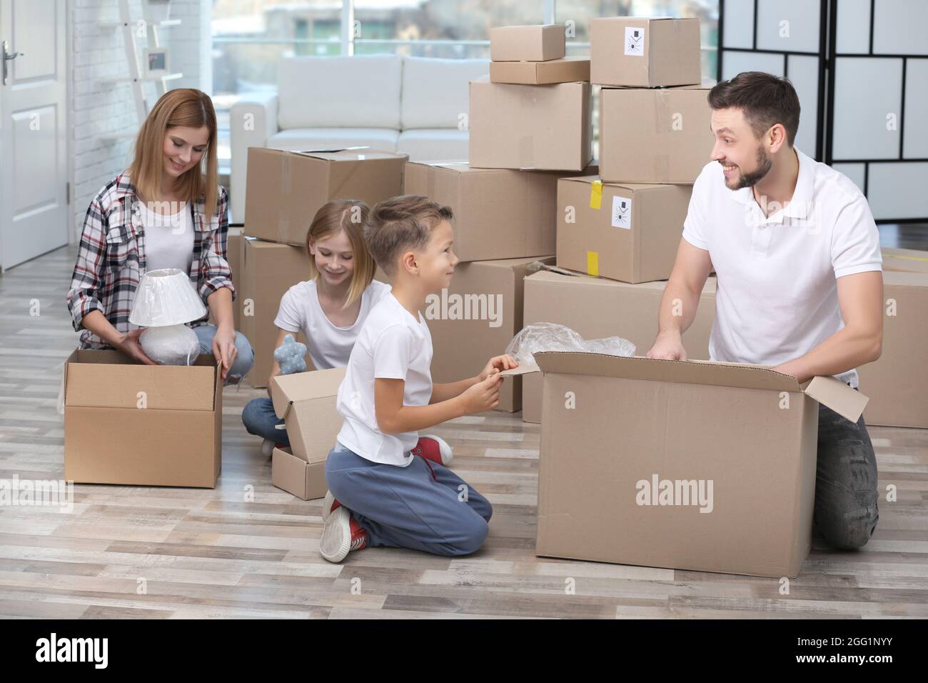 Family unpacking cardboard boxes in new home Stock Photo - Alamy
