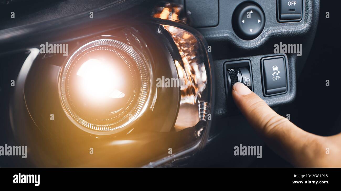 Driver hand adjusting headlight level switch and car headlight bright ...