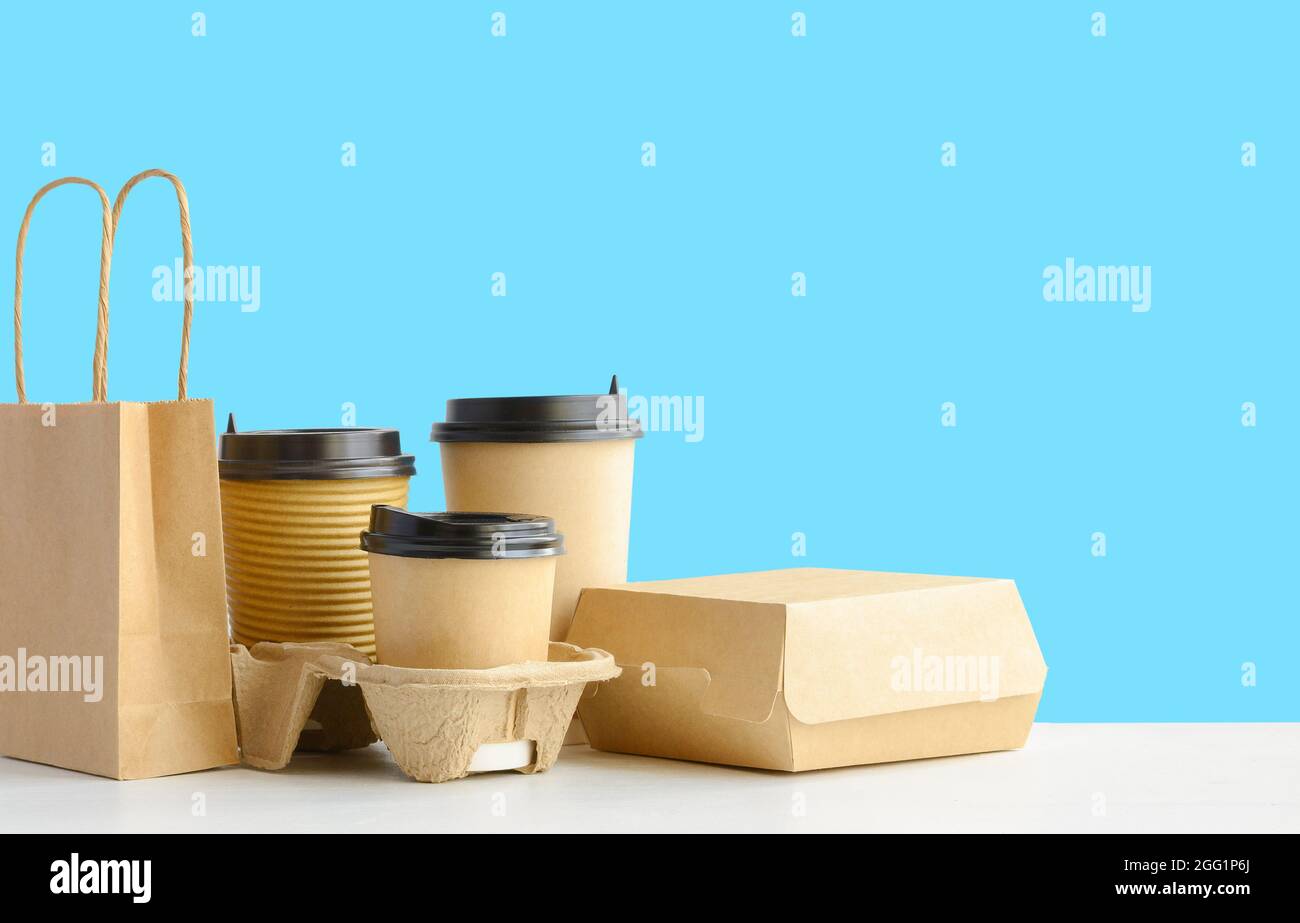 Assortment of food delivery containers on the table on blue wall ...
