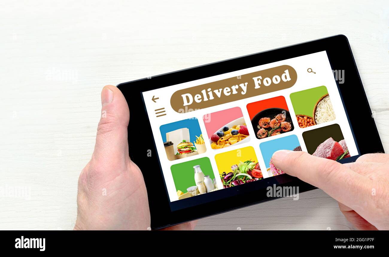 Male hands holding tablet computer with app delivery food on screen ...