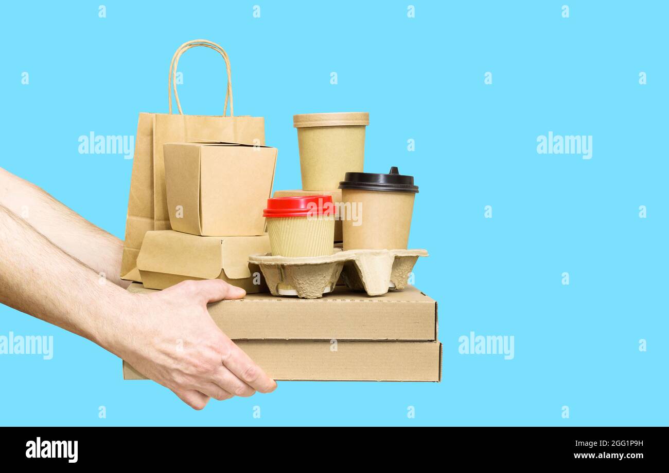 Hands holding assortment of food delivery containers isolated on blue ...