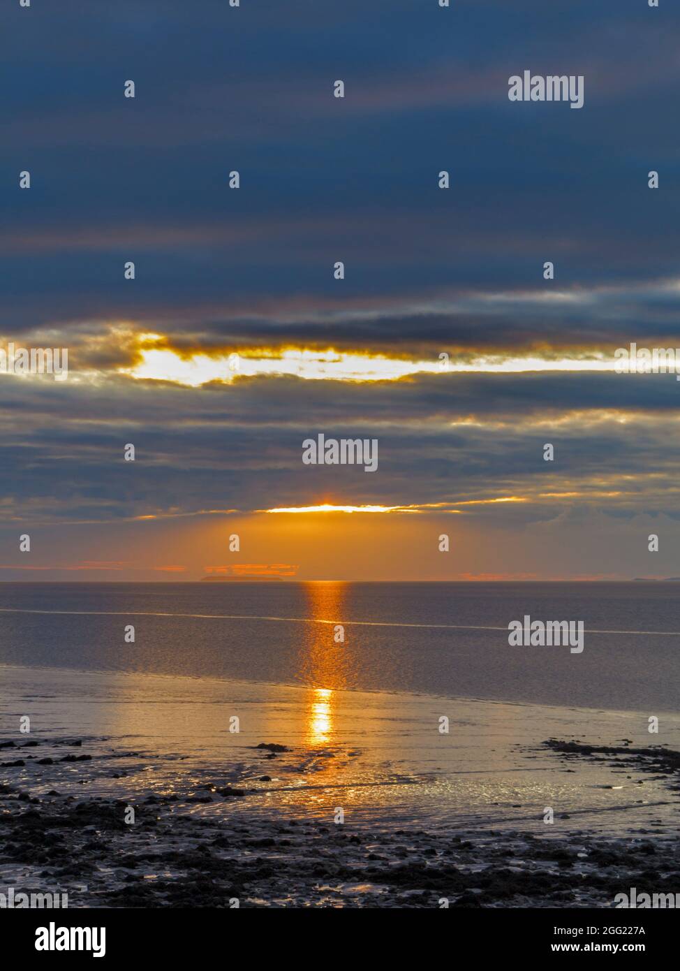 The sun setting over the horizon Stock Photo - Alamy