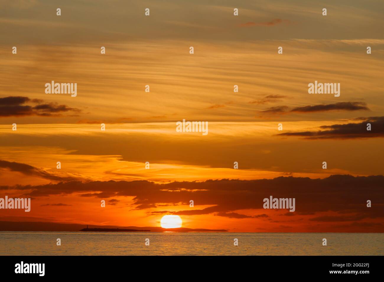 The sun setting over the horizon with cloud and blue sky Stock Photo ...