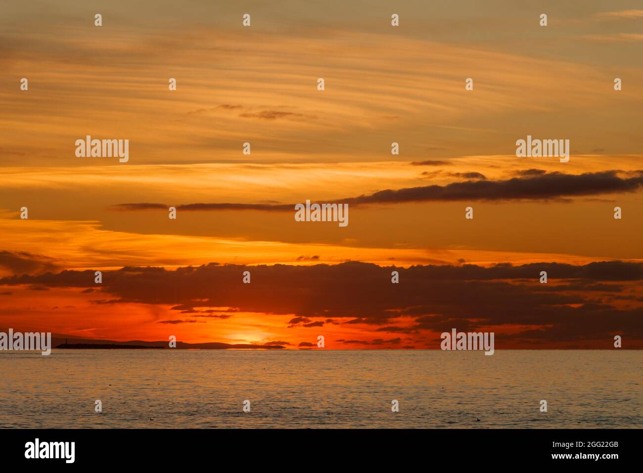 The sun setting over the horizon with cloud and blue sky Stock Photo ...