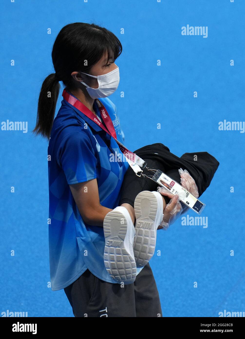 A volunteer carries a set of prosthetic legs at the Tokyo Aquatics ...