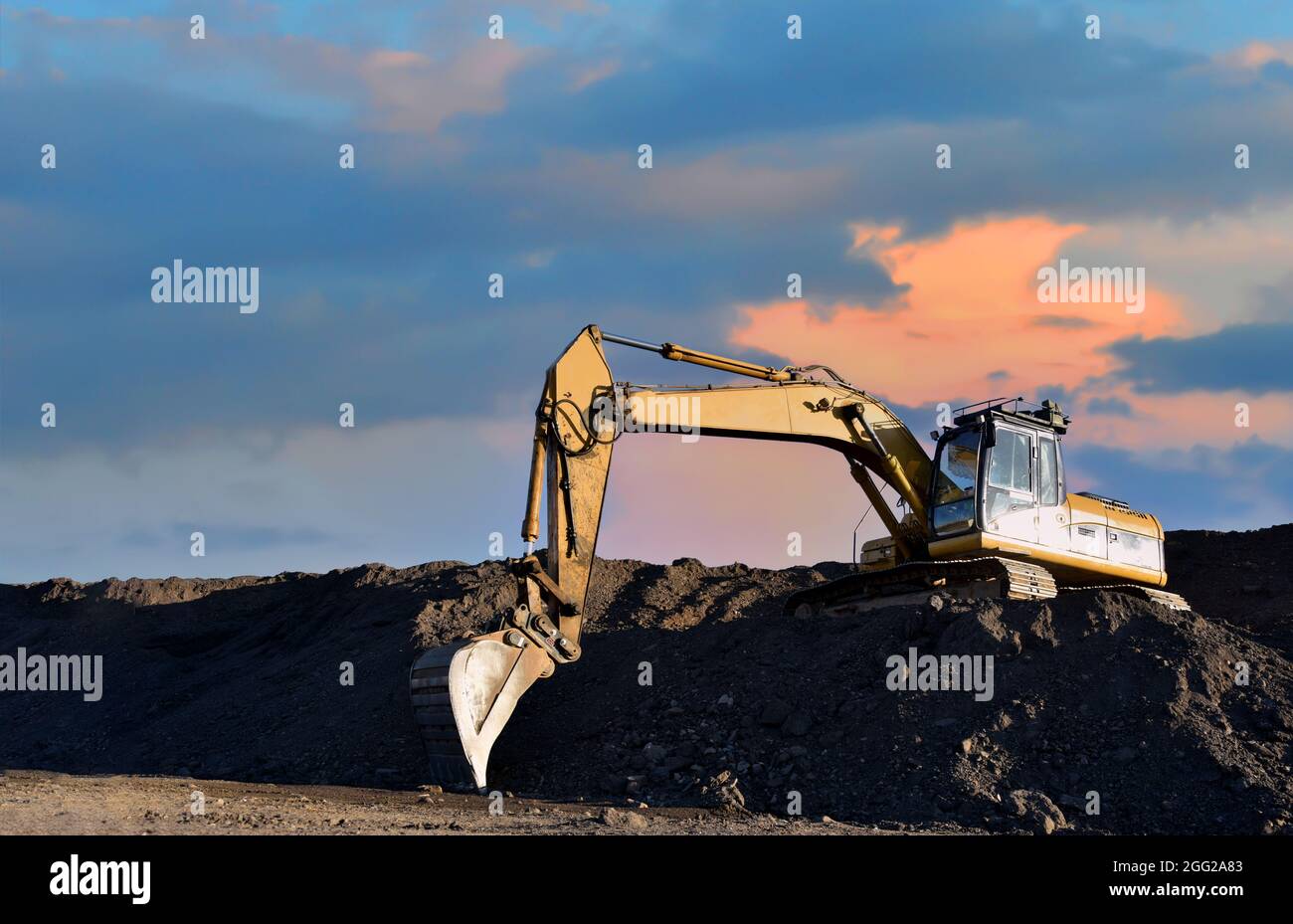Excavator working on earthmoving at open pit mining on sunset ...