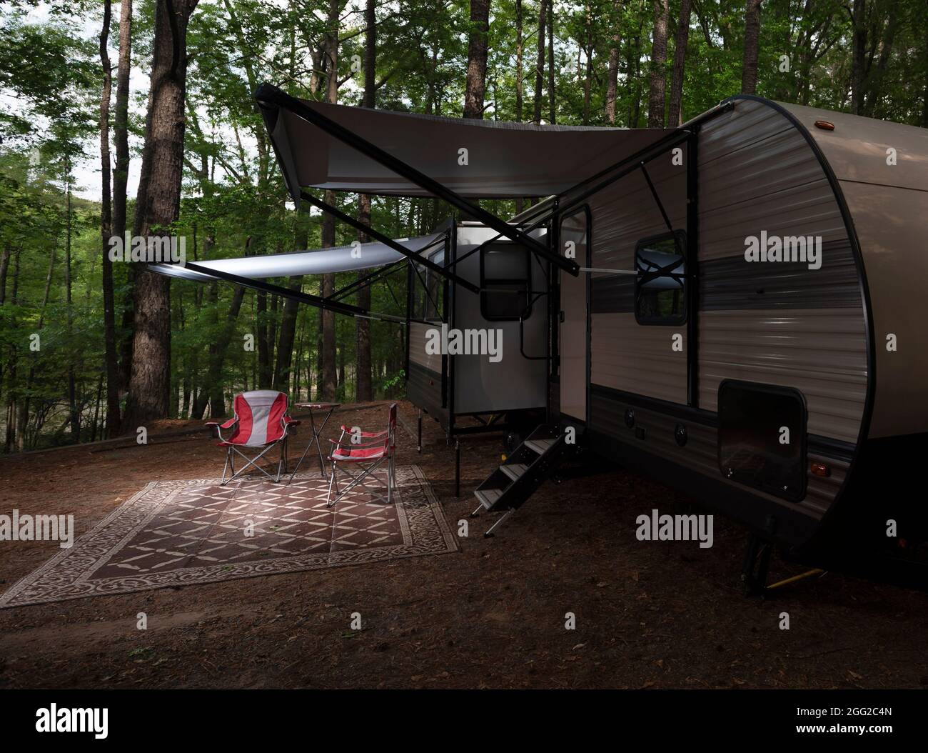 Empty chairs waiting at a camping trailer at a wooded campsite at ...