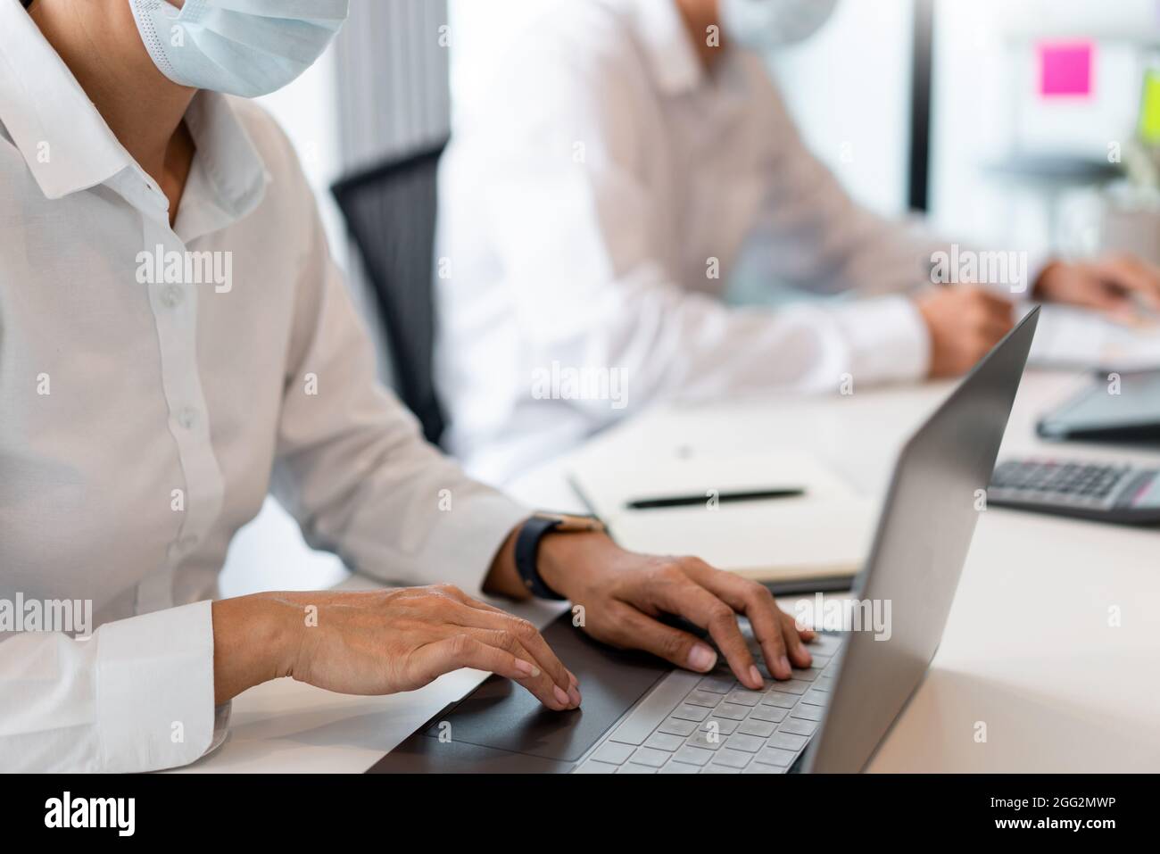 Two colleagues wearing surgical masks analyzing the data in chart for ...