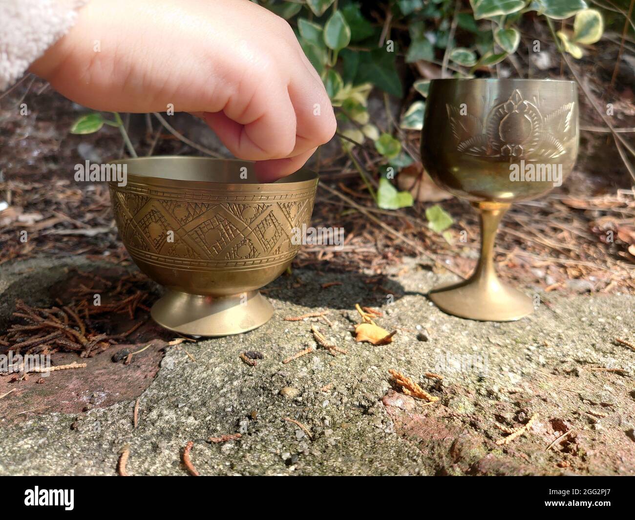 Female hand on top of vintage brass goblets on the ground Stock Photo ...