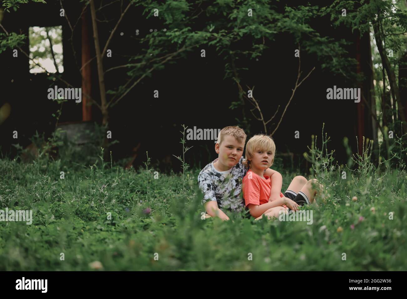 Two brothers sitting together in beautiful natural setting sharing ...
