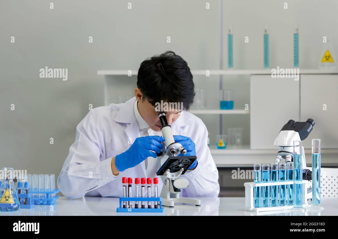 Young asia scientist using a microscope to see the patient's blood ...
