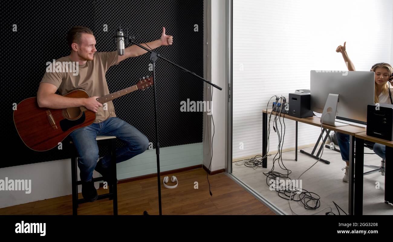 Young caucasian artist with acoustic guitar checks the correctness of ...