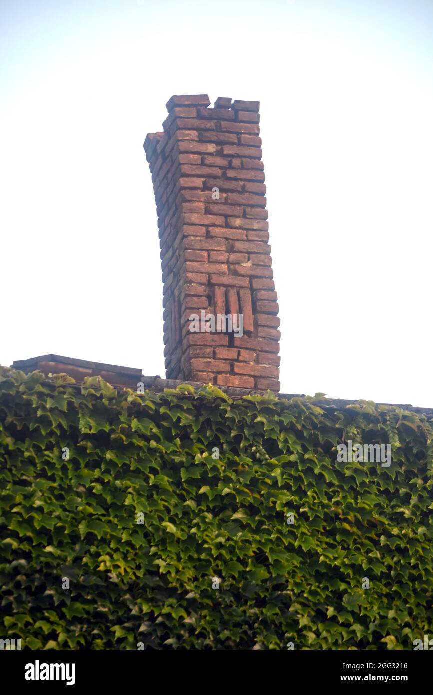 Damaged falling roof and chimney on sunny day with clear blue sky on an ...