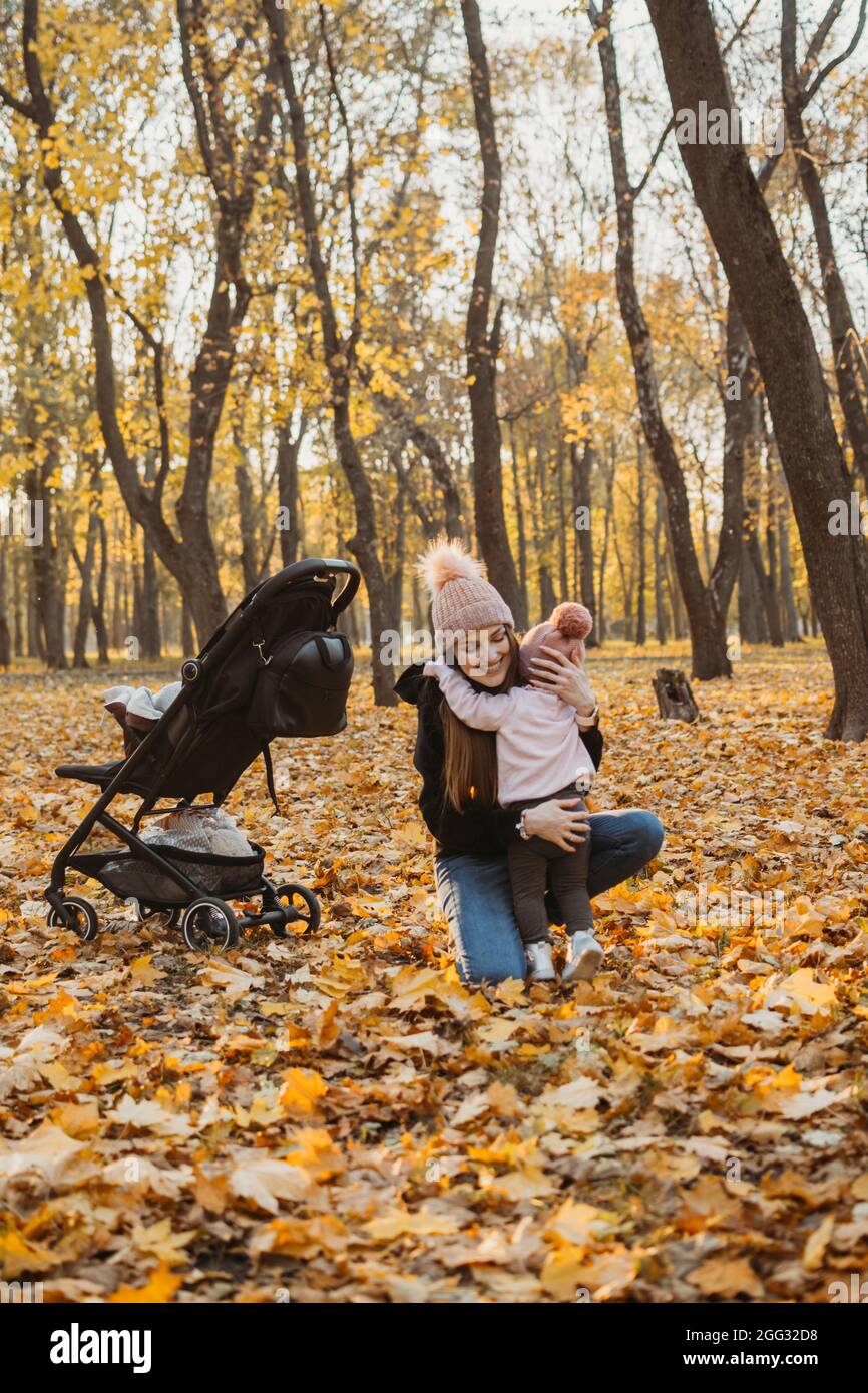 Mom and toddler baby daughter are walking in autumn park with baby ...