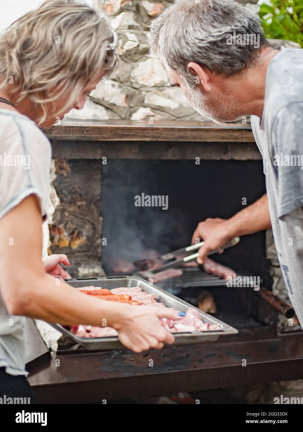 BBQ grilling party. Couple in garden making barbecue grill. Food ...