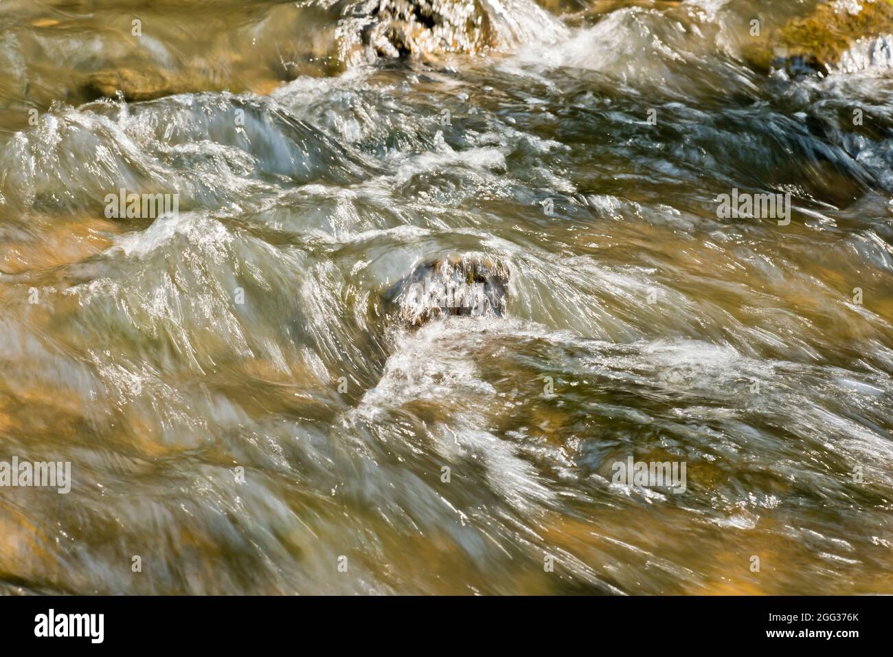 Water flowing over rocks in a stream using long exposure photography ...