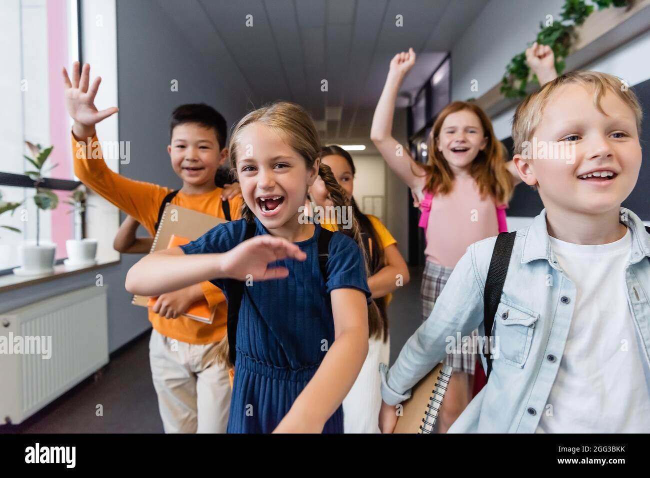 excited multiethnic classmates waving hands and showing win gesture in ...