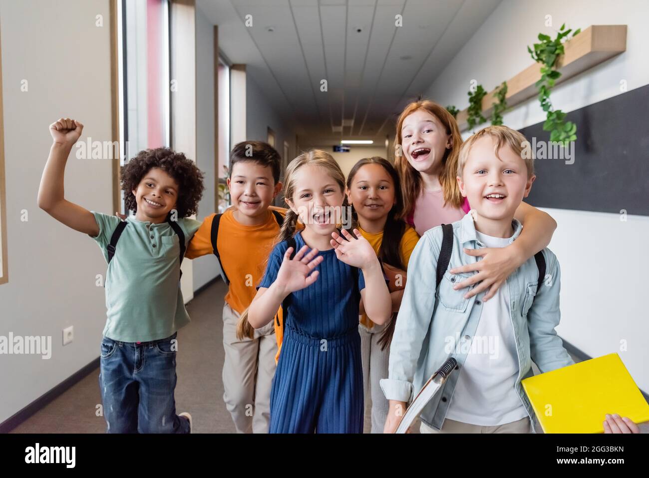 cheerful multiethnic kids embracing, waving hands and showing rejoice ...