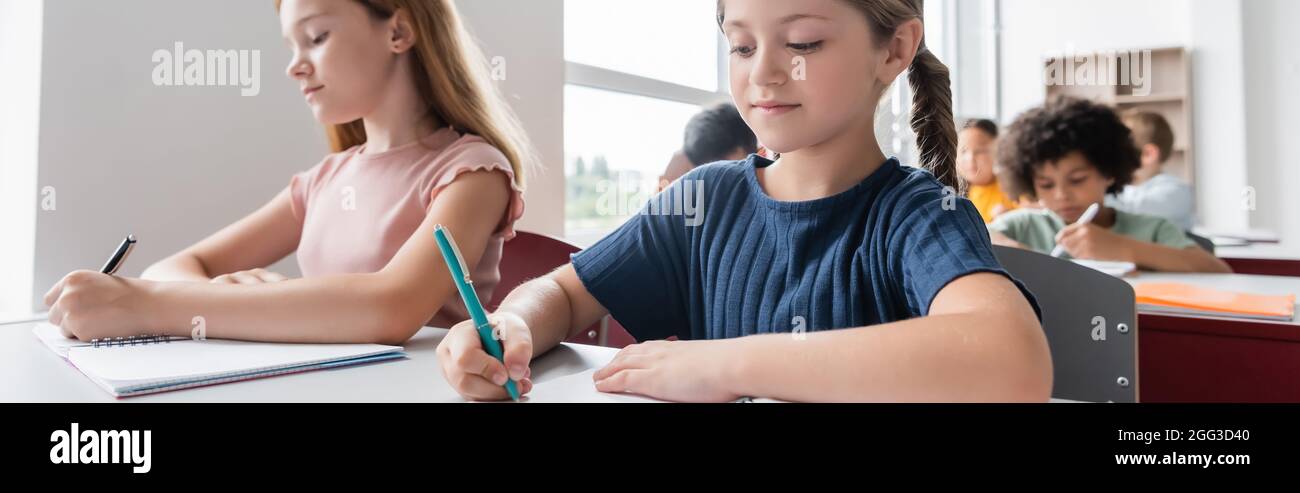 multiethnic pupils writing in notebooks during lesson, banner Stock ...
