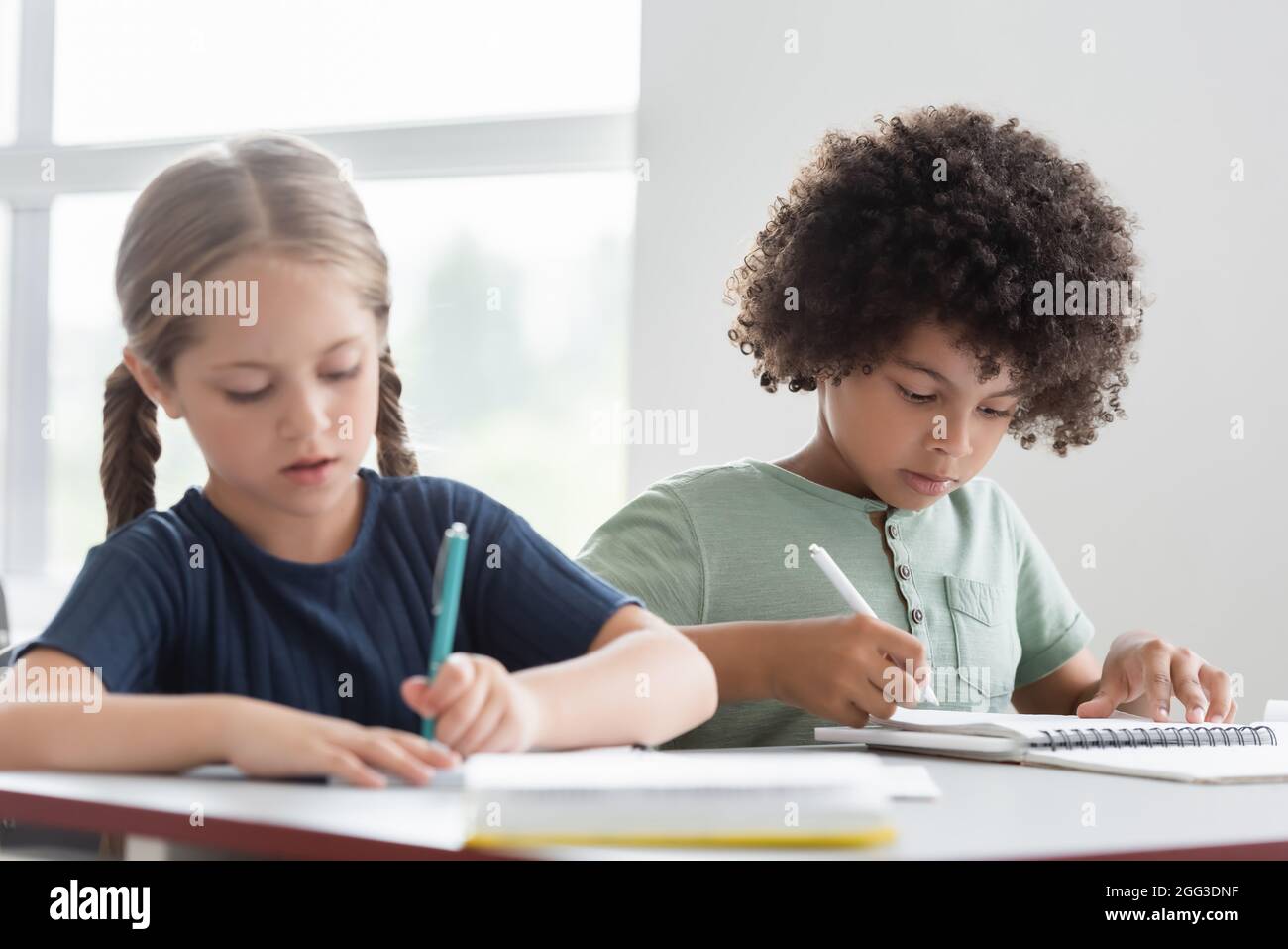 interracial kids writing in notebooks during lesson Stock Photo - Alamy