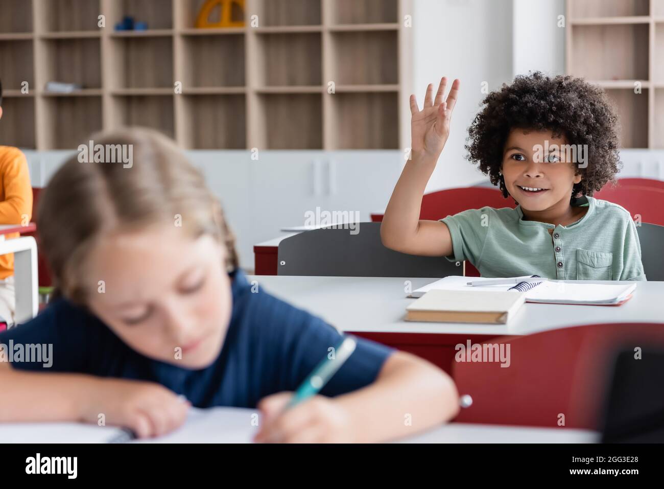 Boy raising hand in classroom hi-res stock photography and images - Alamy