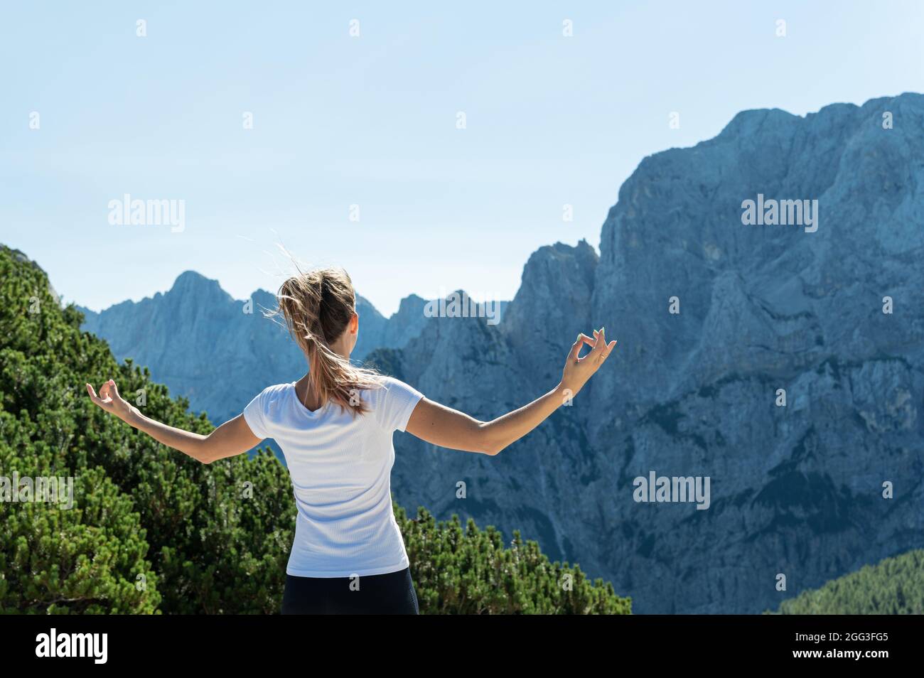View from behind of a young woman taking a break to meditate outside in ...