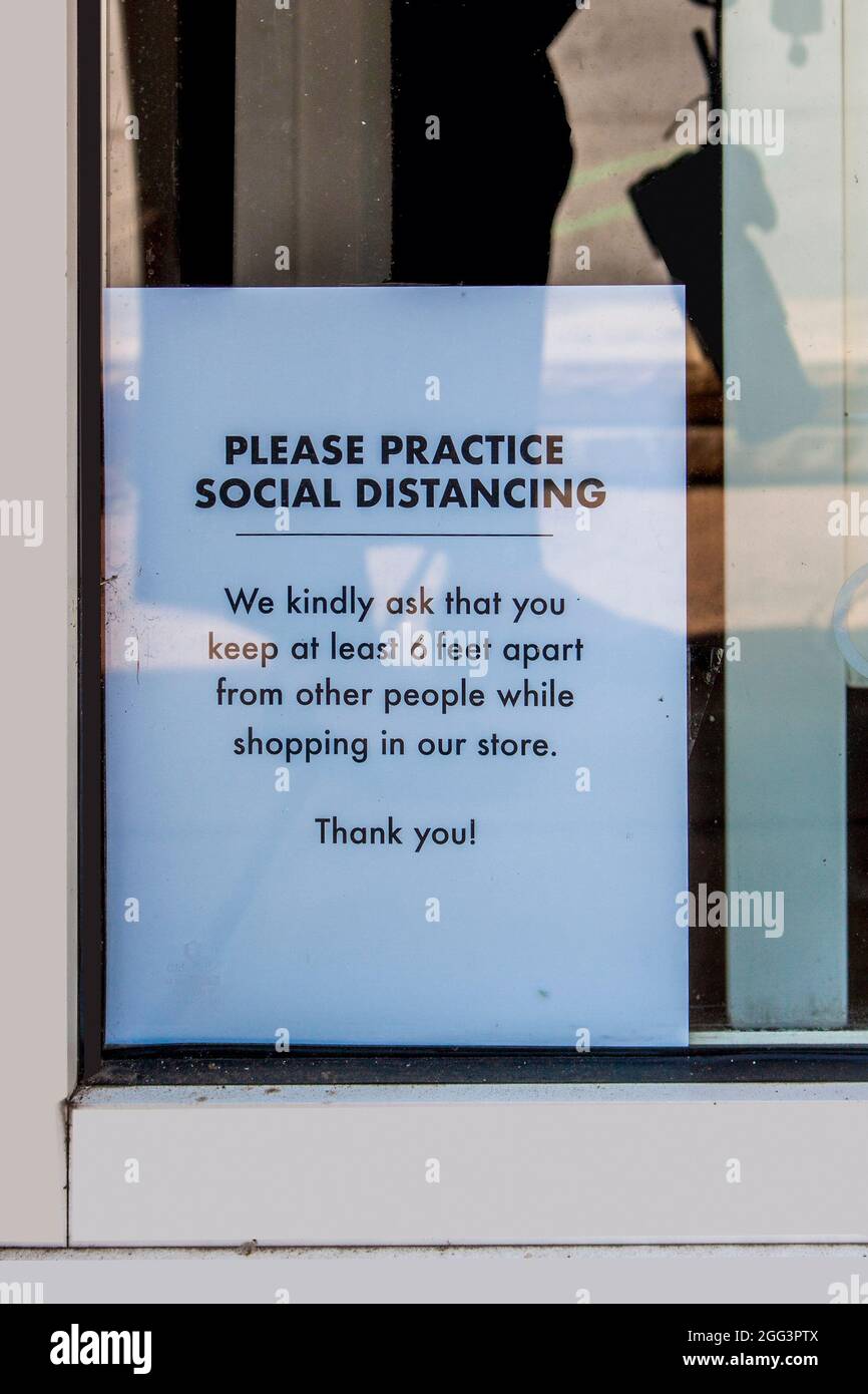 Social Distancing sign in shot window printed on white paper with a few ...