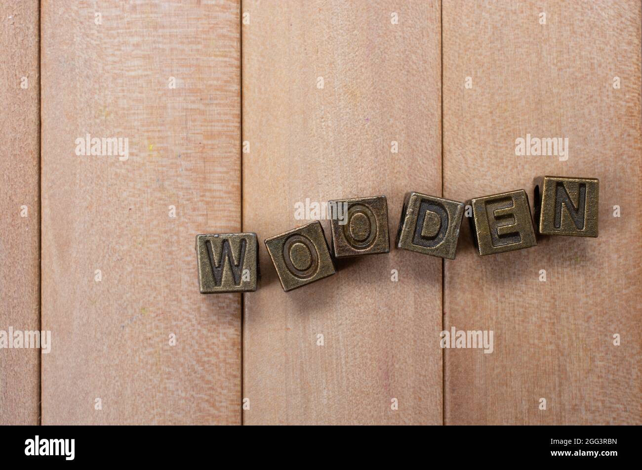 Metallic blocks forming a word "WOODEN" on plank surface Stock Photo ...