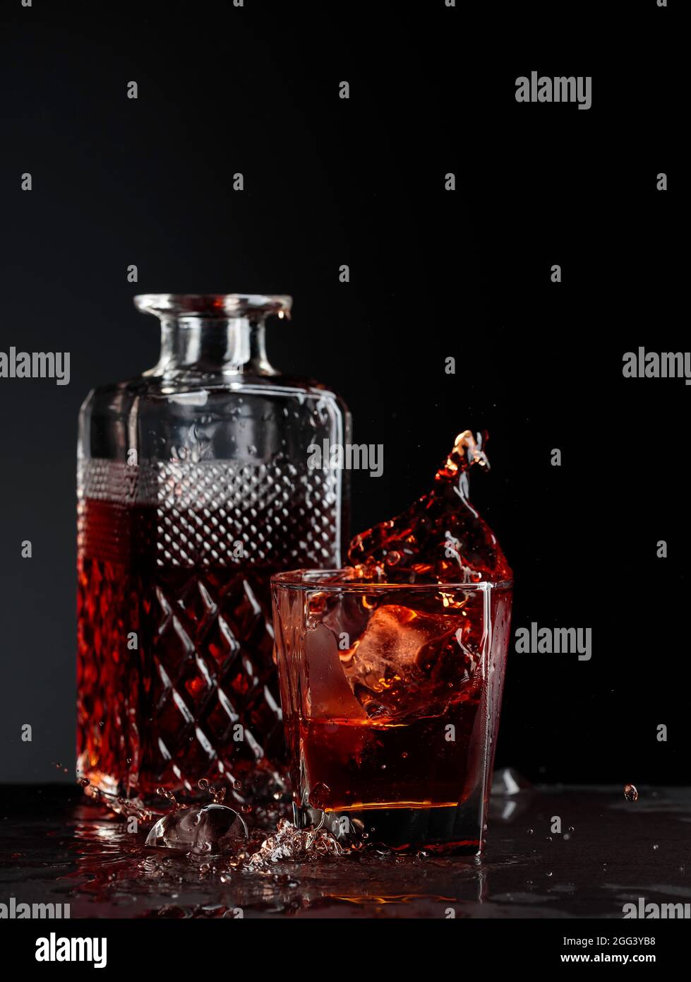 Pieces of ice fall into a frosted glass with whiskey. Alcoholic drink ...