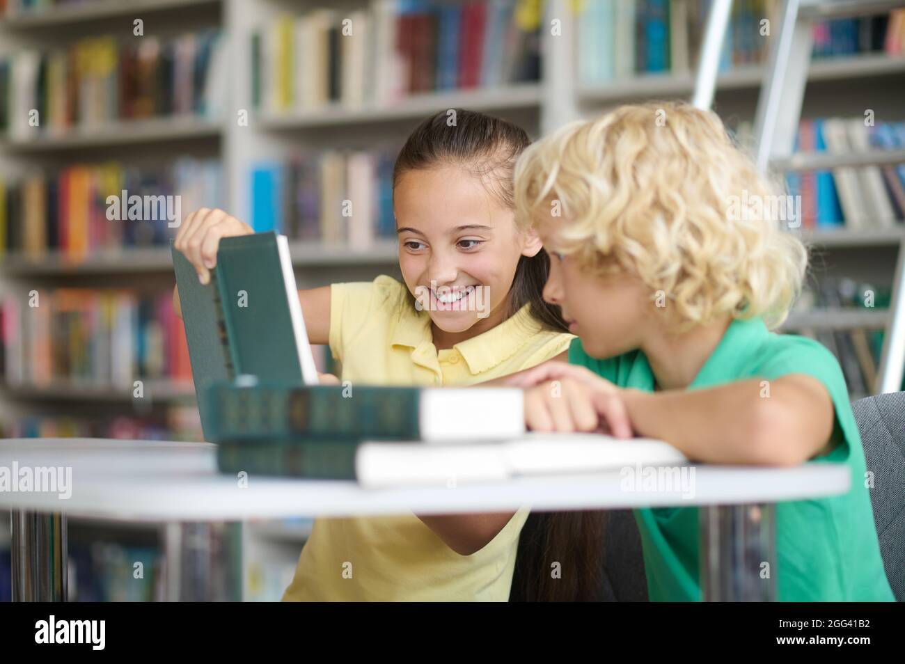 Two classmates doing their homework at the library desk Stock Photo - Alamy