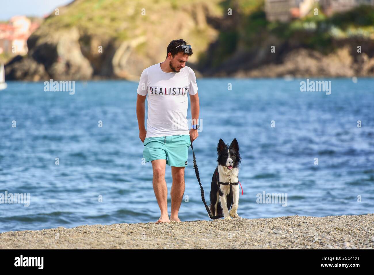 Beautiful shot of a Hispanic male walking his dog at a beach in Andorra ...