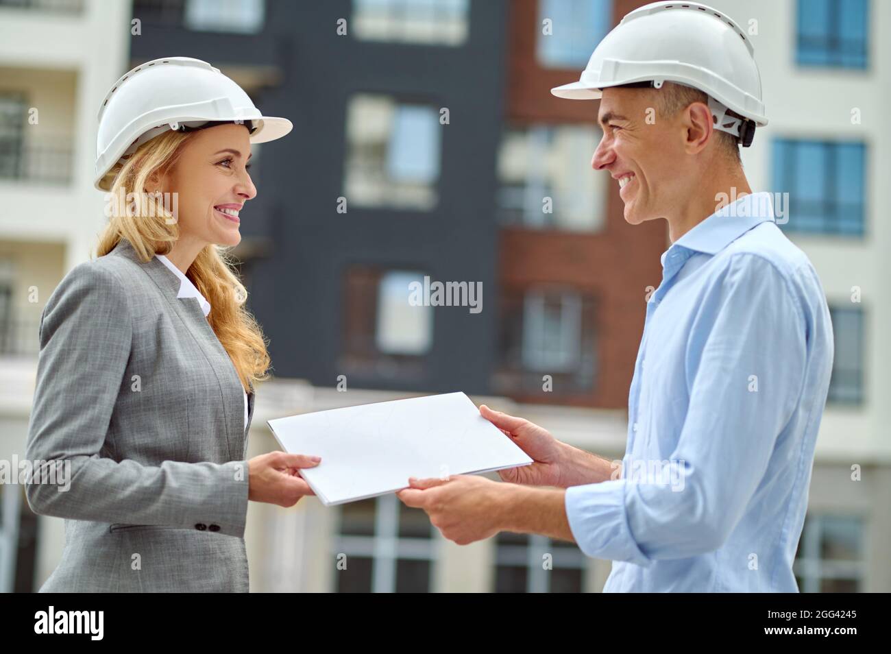 Supervisor handing over the building documentation to a joyous worker ...