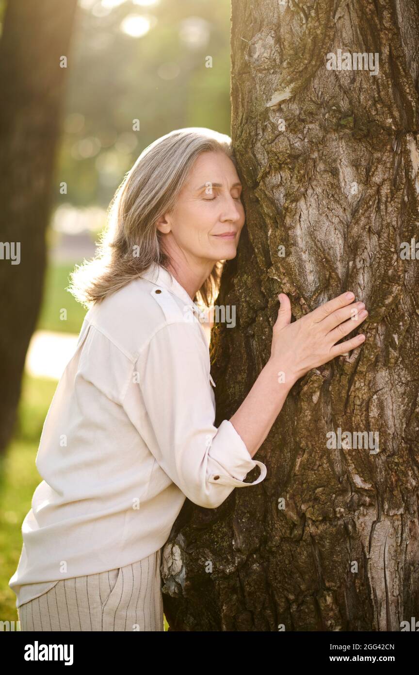 Woman with closed eyes touching tree Stock Photo - Alamy