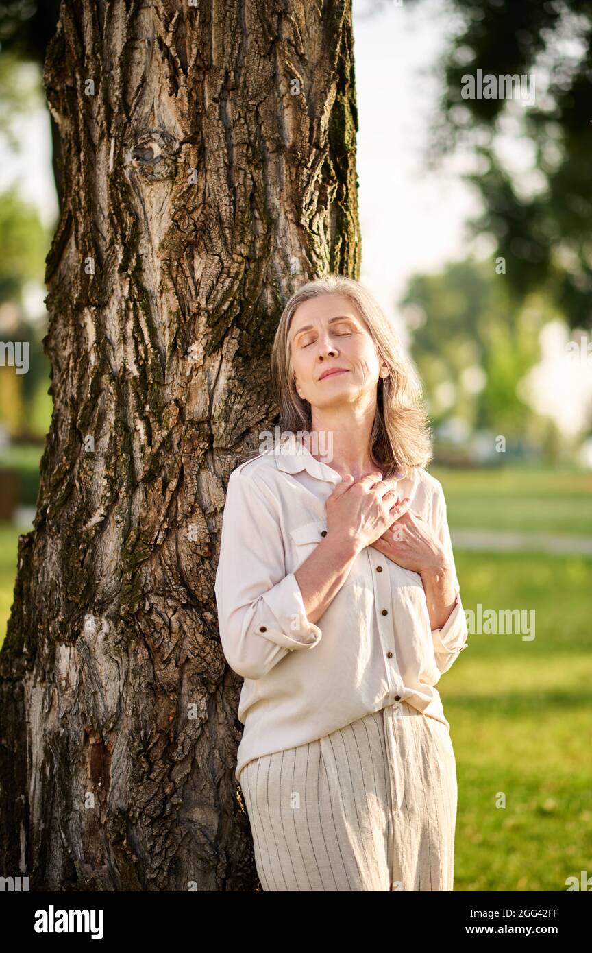 Woman folded palms on chest near tree Stock Photo - Alamy