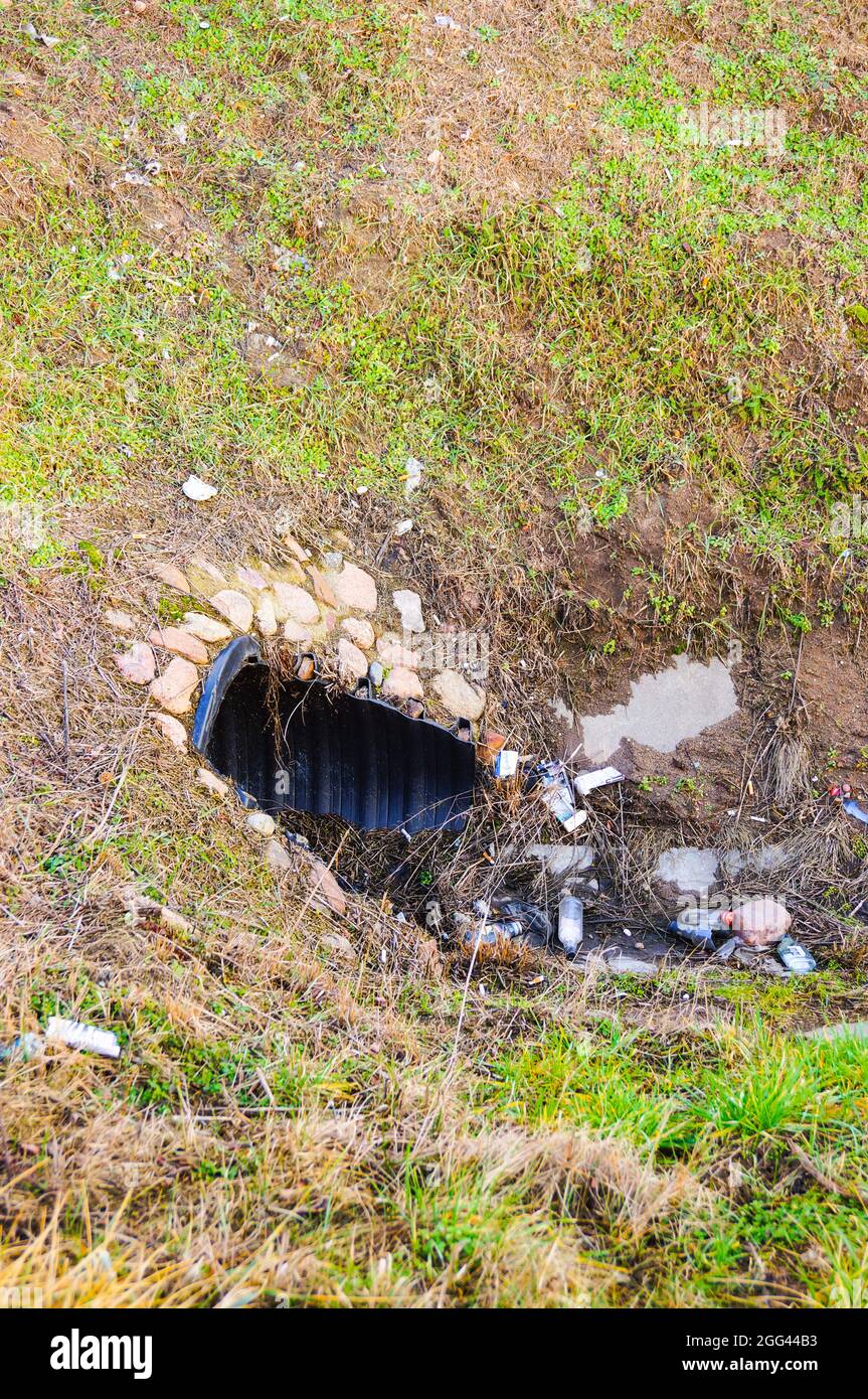 Vertical shot of trash by an exit of a canal with weeds and grass Stock ...