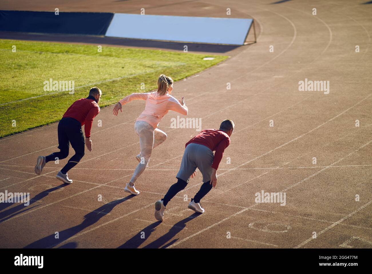 Group of young athletic sprinters at starting position ready for race ...