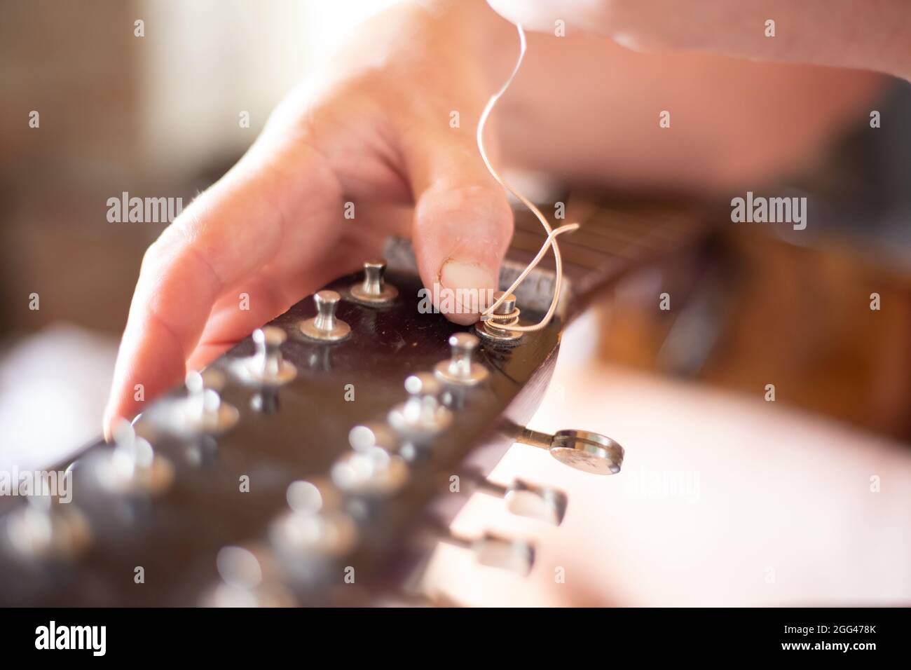 Repair of an old guitar. The man pulls the strings on the fretboard ...