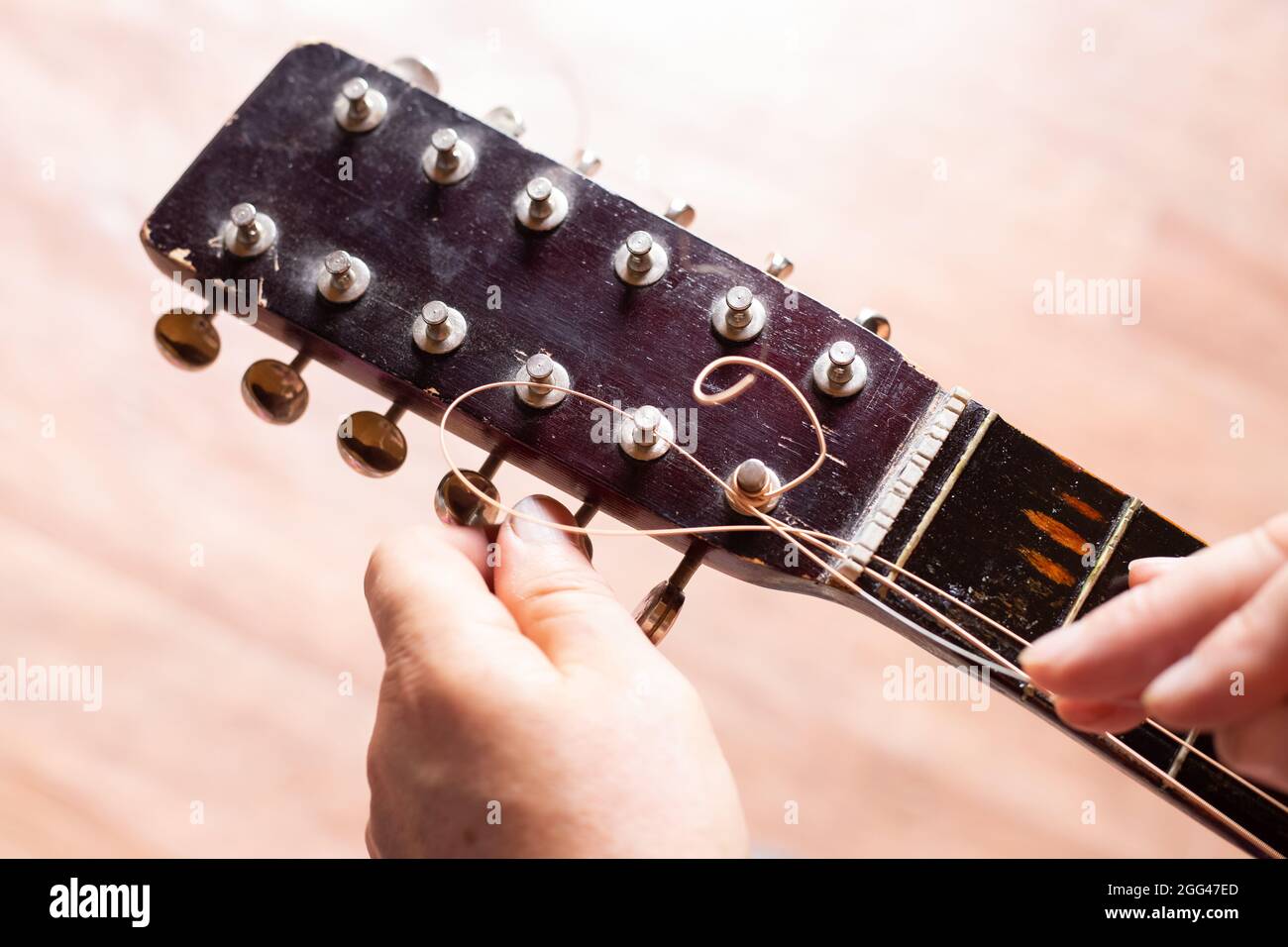 Repair of an old guitar. The man pulls the strings on the fretboard ...