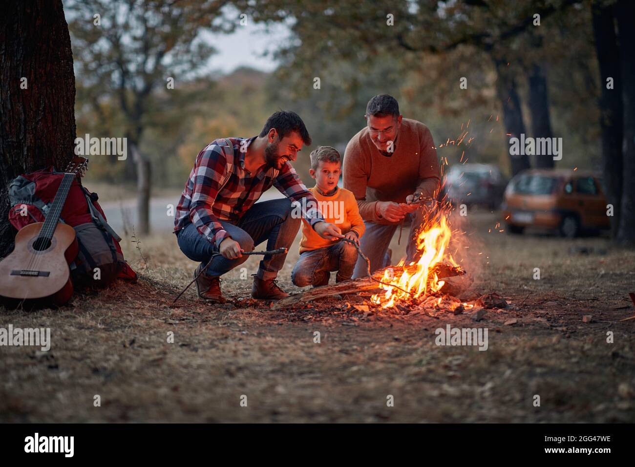 Father, son and grandson enjoying a campfire in the forest on a ...