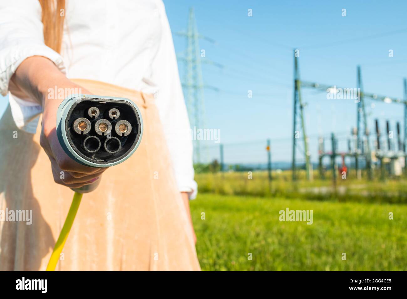 Woman unplugging electric car charger at a charging station near ...