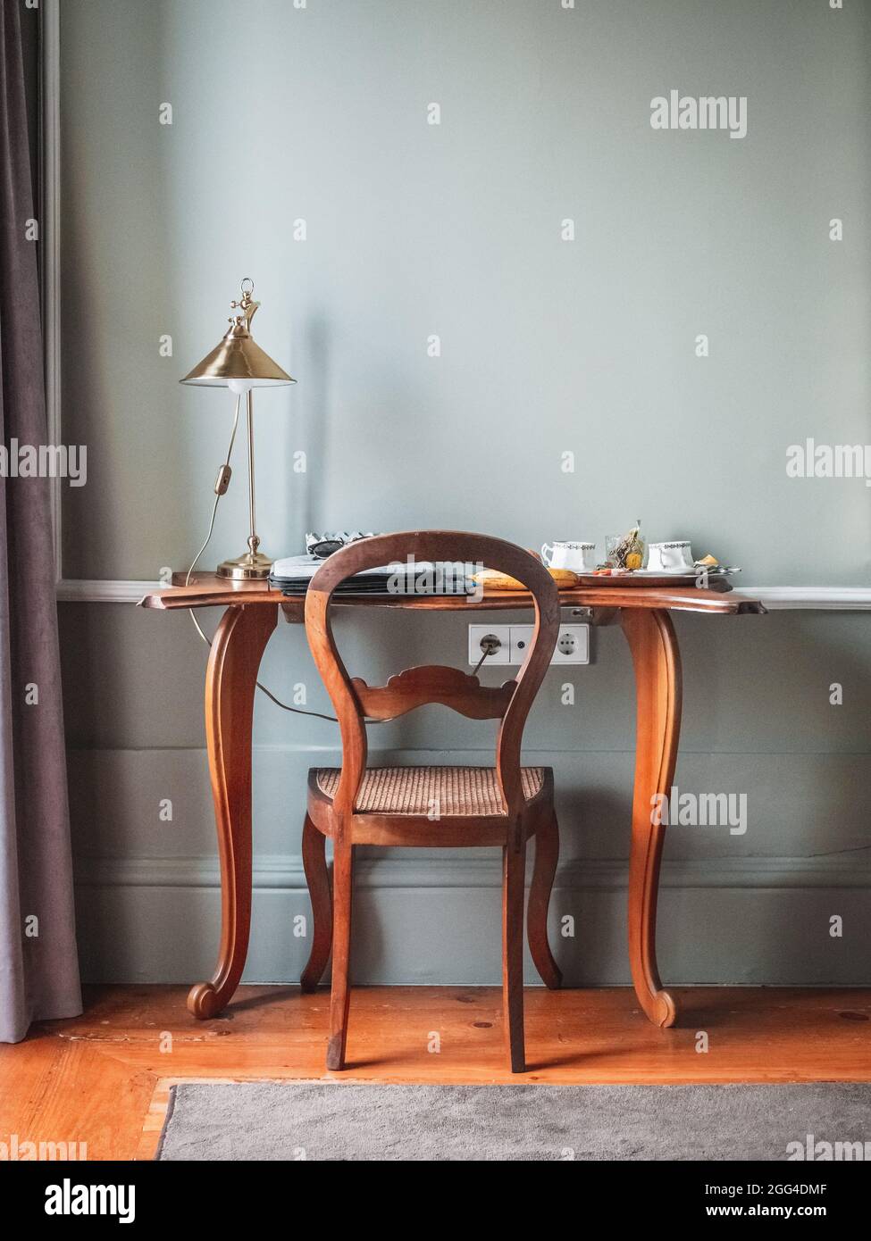 Vertical shot of a beautiful wooden desk with a chair and a small lamp ...