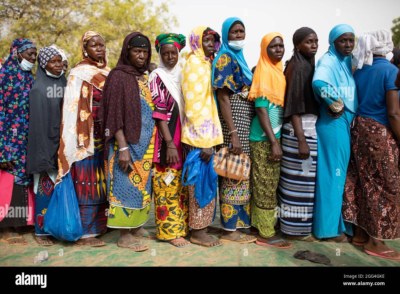 Women line up to receive food assistance at a IDP camp distribution ...