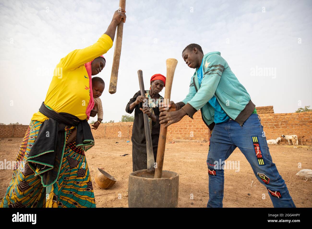 A family works together to grind flour for their next meal using a ...