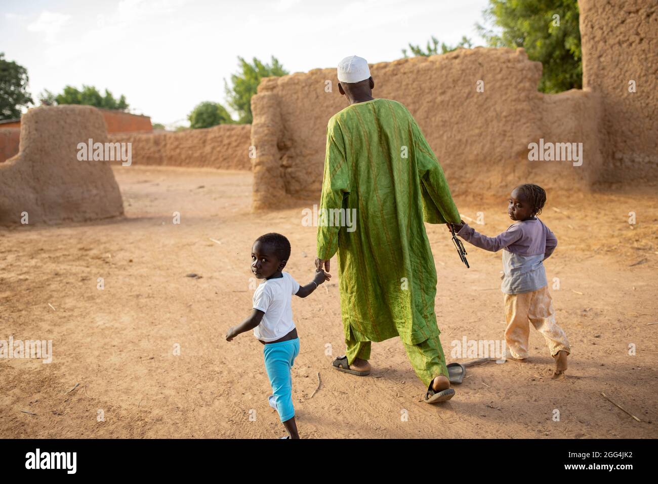 African father walking with his two children through their traditional ...