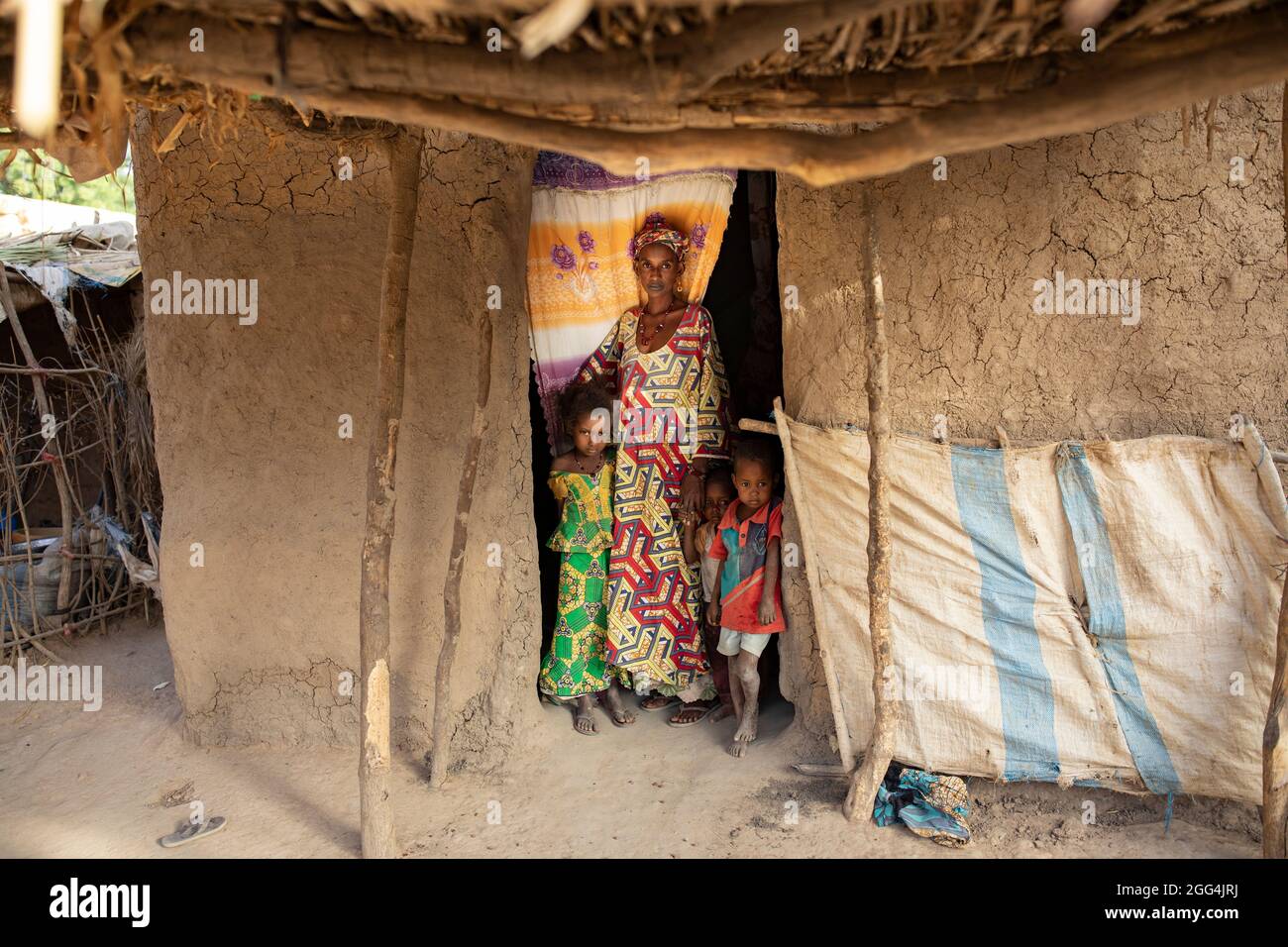 A Fulani mother and her three children stand together in the doorway of ...