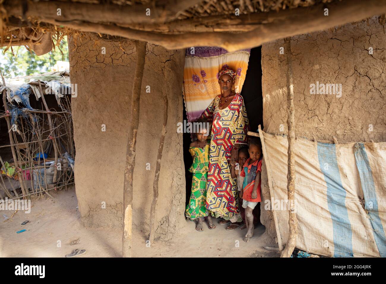 A Fulani mother and her three children stand together in the doorway of ...