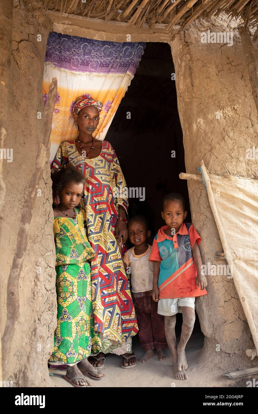 A Fulani mother and her three children stand together in the doorway of ...