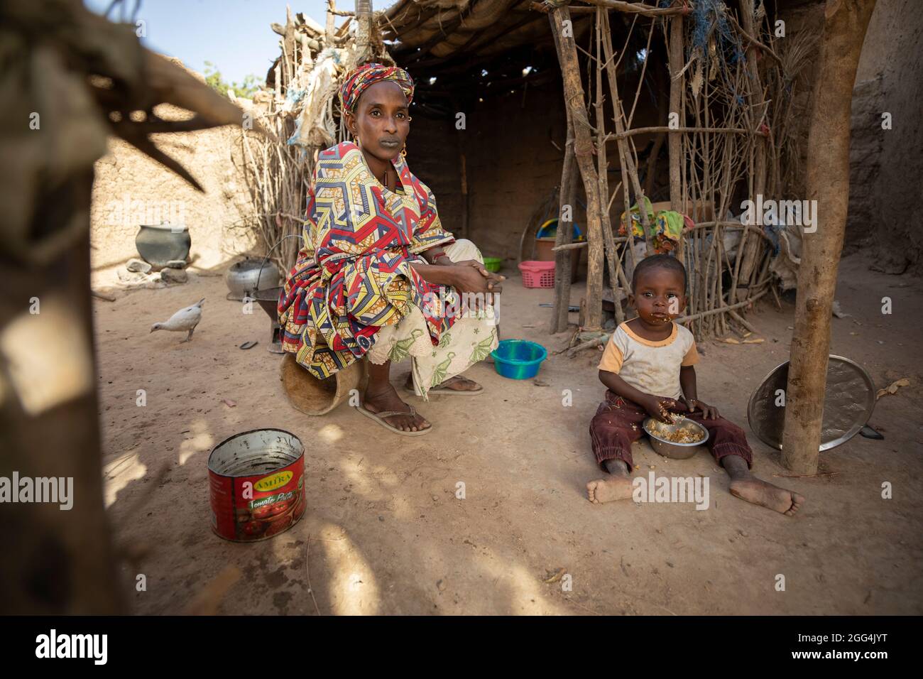 A Fulani African woman and her baby boy in front of their small hut in ...