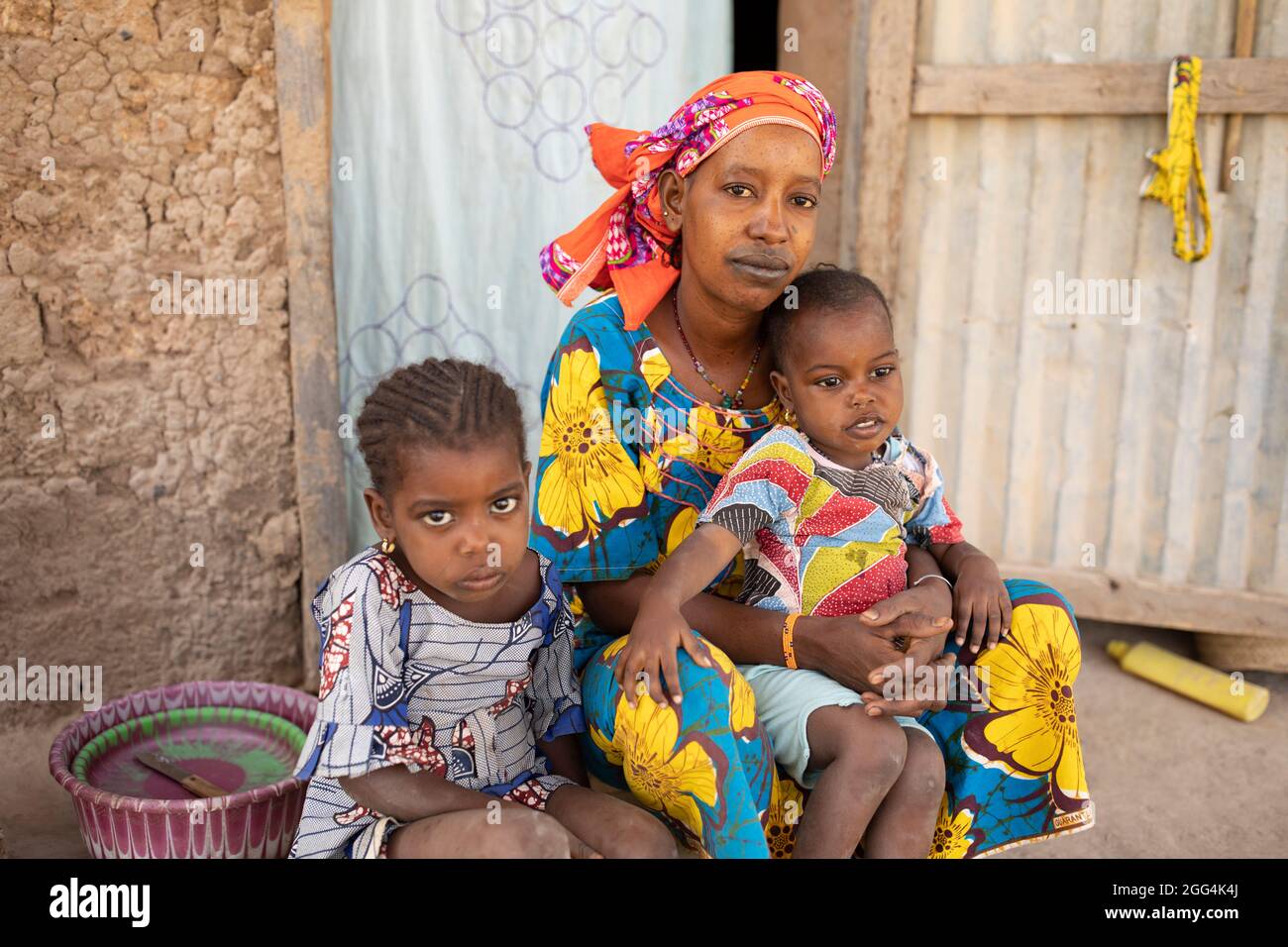 A young single Fulani mother and her two daughters sit in the doorway ...